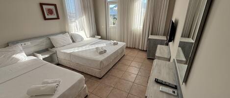 Quarto de hotel com duas camas, televisão, minibar e janela com cortinas.