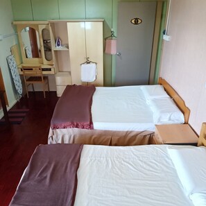 Quarto com duas camas, uma escrivaninha, um guarda-roupa e um espelho.