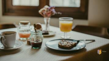 Uma mesa de café da manhã com uma xícara de café, um copo de suco de laranja, um pote de geleia e uma fatia de torrada.