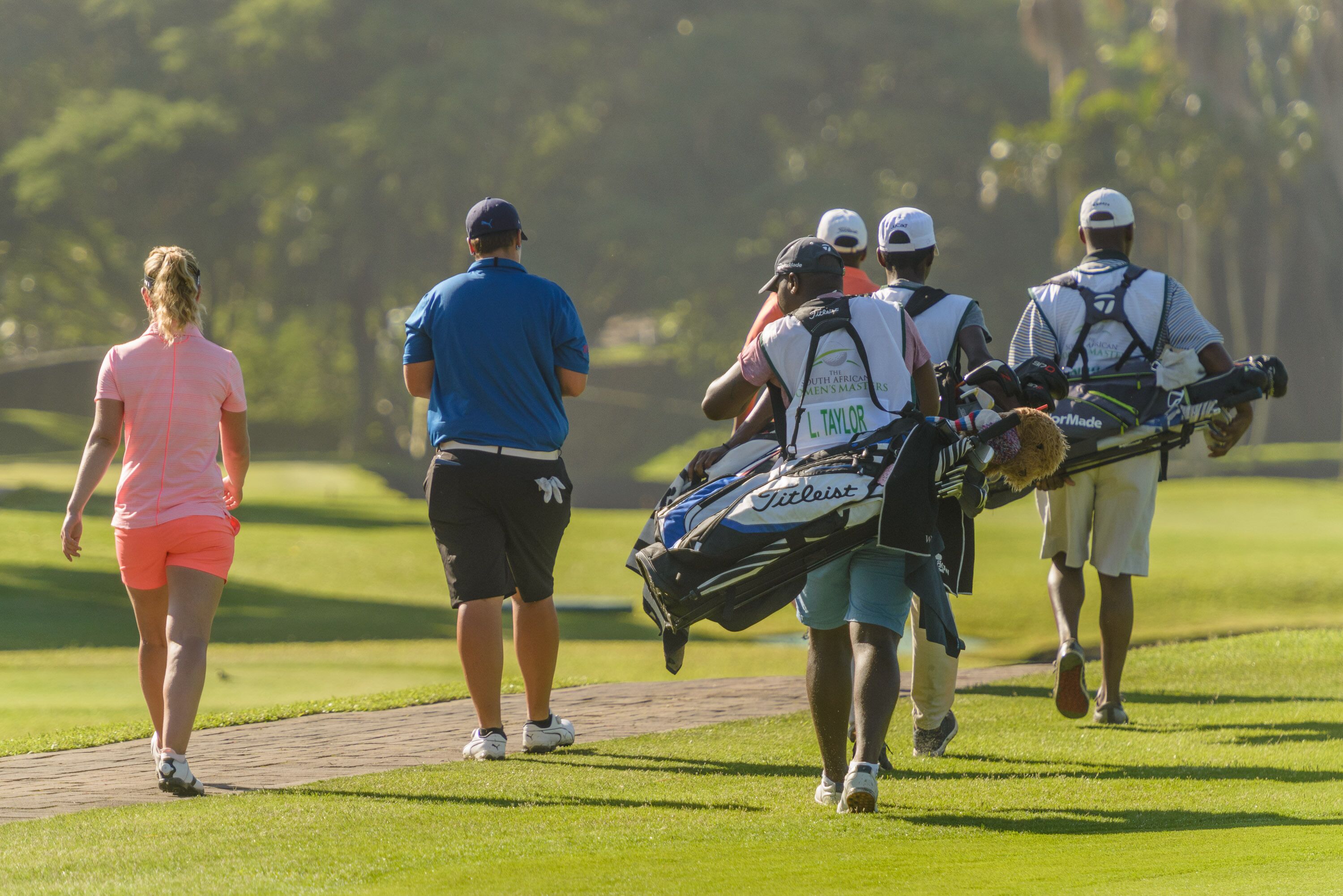 Um campo de golfe com jogadores caminhando por um caminho.