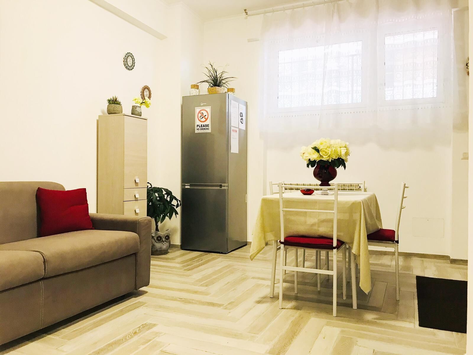 Um espaço compacto com sofá, mesa de jantar com cadeiras, frigorífico e uma planta em vaso.
