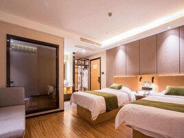 Quarto de hotel com duas camas, um espaço de estar e um espelho.
