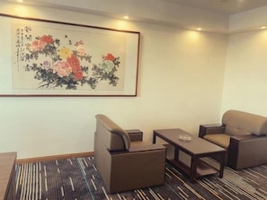 Quarto com pintura tradicional japonesa, um sofá, uma mesa e piso coberto por carpete.