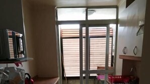 Uma cozinha compacta com uma porta de vidro deslizante para uma varanda, uma pia e um pequeno espaço de refeições.