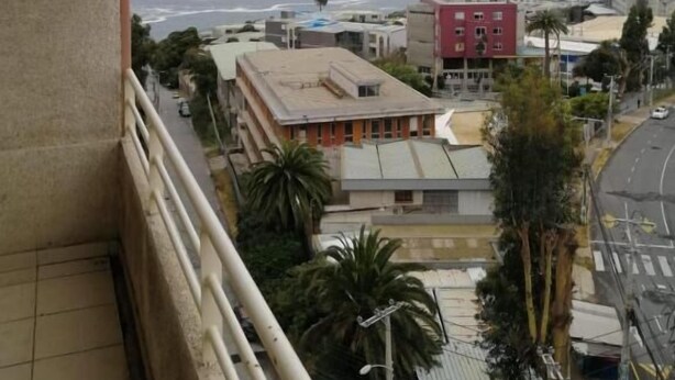 Varanda com vista para a paisagem urbana, edifícios e o oceano.