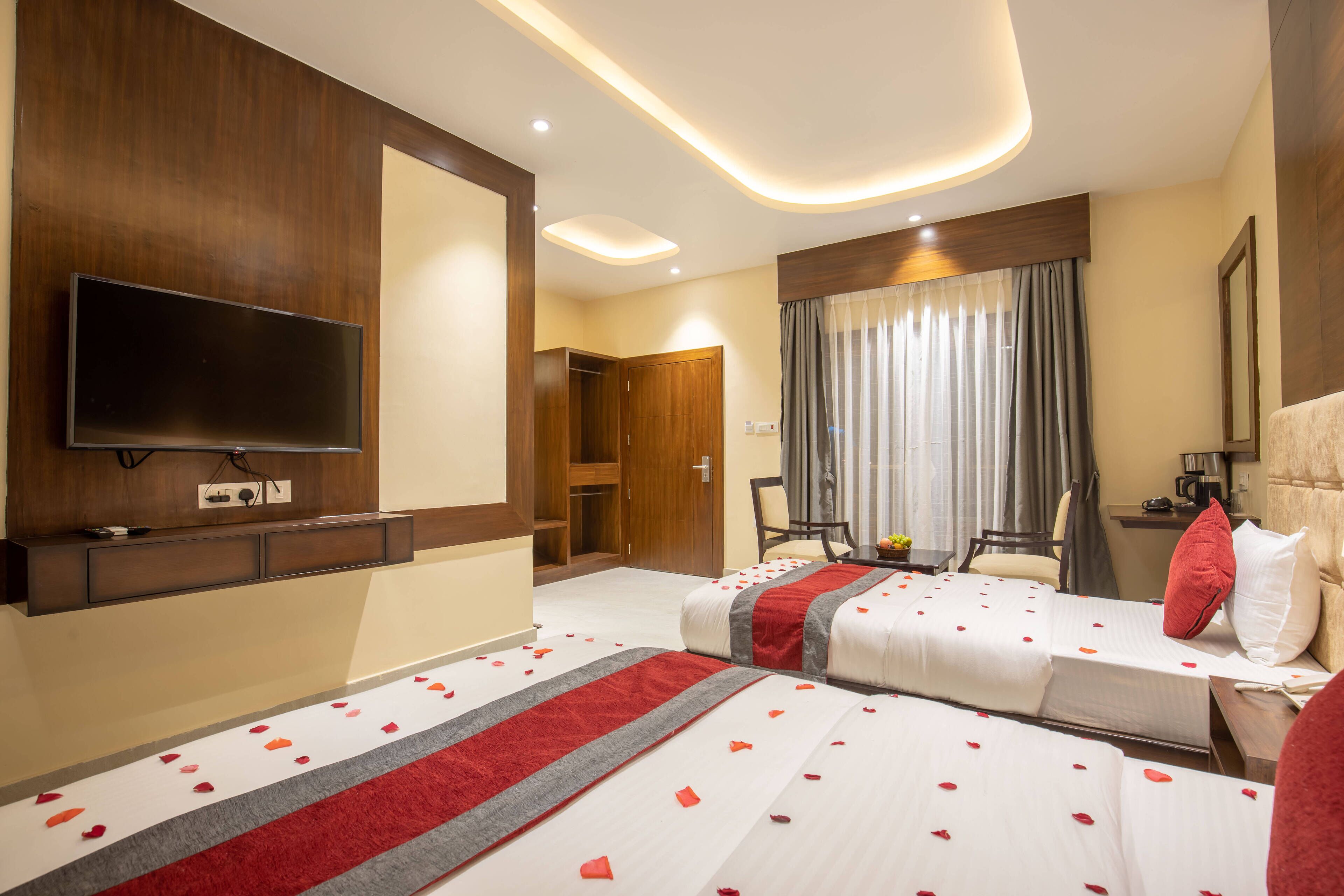 Quarto de hotel com duas camas, televisão, escrivaninha e uma cadeira.