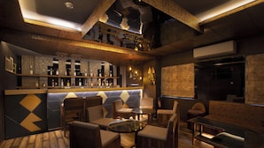 Uma área de bar com mobiliário de madeira, um balcão e prateleiras com garrafas.