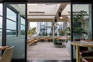 Um restaurante moderno com terraço, amplas janelas e área de estar interna.