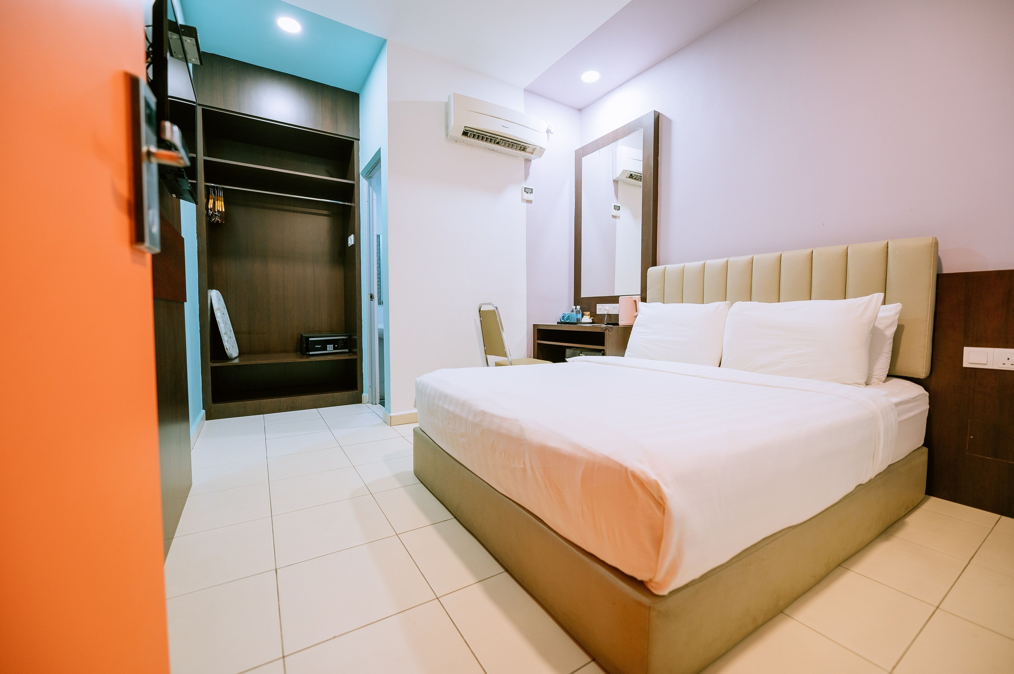 Quarto de hotel com uma cama grande, um guarda-roupa, uma mesa de cabeceira e um aparelho de ar condicionado.