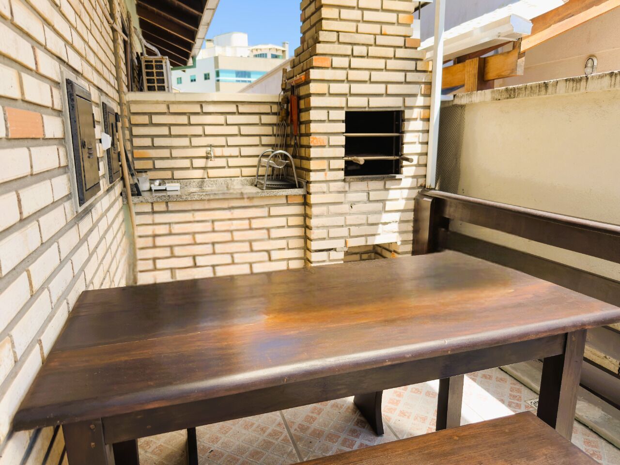 Pared de tijolos com grade de metal e um banco de madeira.