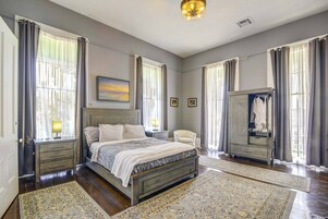 Quarto com cama grande, guarda-roupa, mesa de cabeceira e uma cadeira.