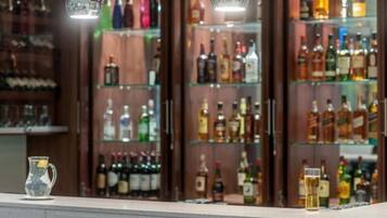 Uma área de bar com prateleiras cheias de garrafas de bebidas e alguns copos no balcão.