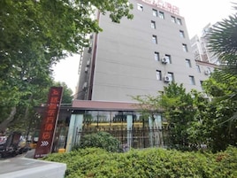 Edifício de vários andares com design moderno, fachada de vidro e placa vermelha com texto branco.
