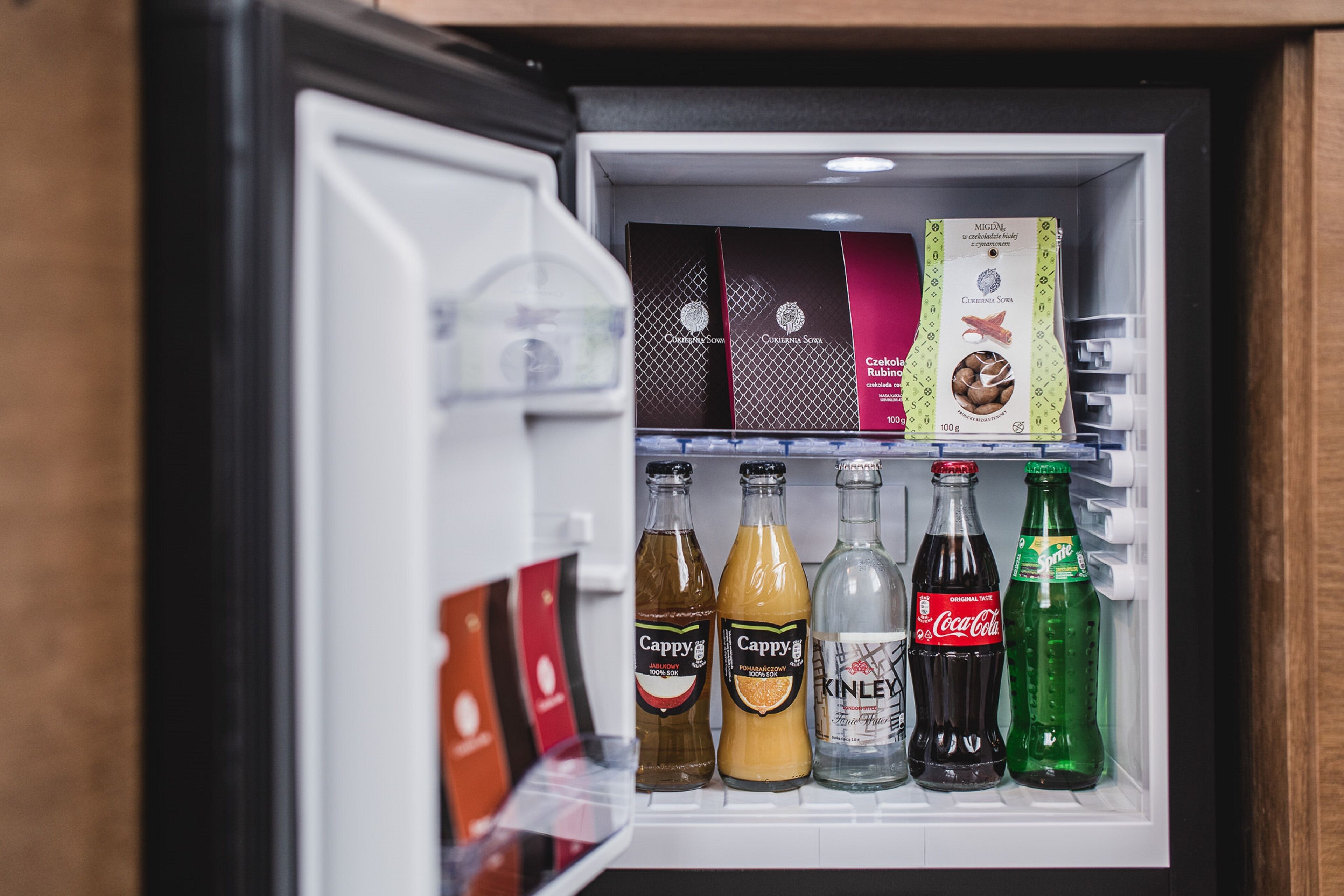 Uma geladeira com diversas bebidas e produtos embalados.