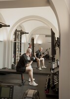 Academia com equipamentos de exercício, espelho e suporte para pesos.