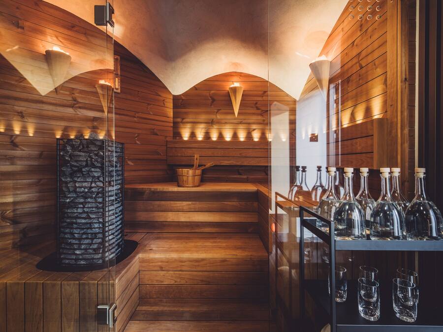 Interior em madeira com lareira de pedra, degraus de madeira e um espaço de bar com garrafas e copos.