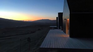 Um edifício moderno com um deck de madeira e vista para a paisagem.