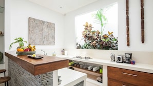 Uma cozinha moderna com uma ilha central, uma janela ampla com vista para plantas e um objeto decorativo na parede.