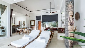 Quarto de hotel moderno com duas camas de madeira, área de refeições e sala de estar.