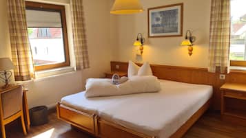 Quarto com cama de madeira, duas luminárias de cabeceira, janela com cortinas, radiador e quadro na parede.
