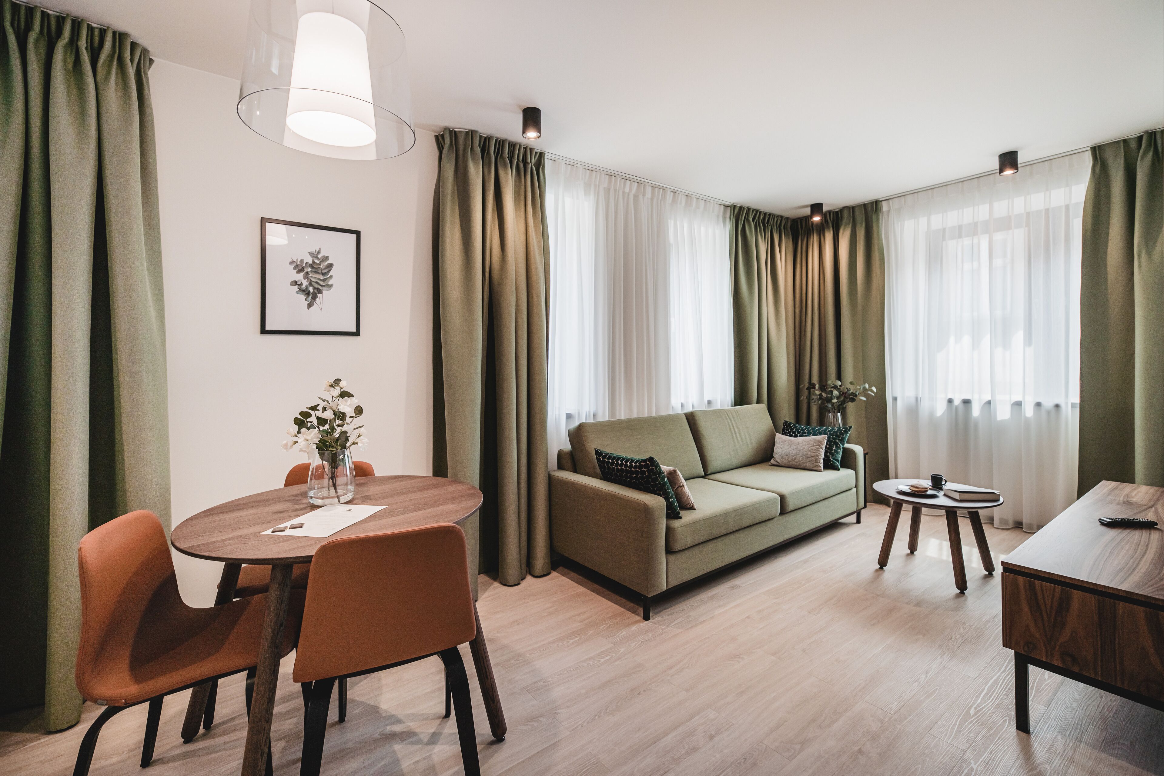 Uma sala de estar moderna com um sofá, uma mesa de jantar com cadeiras e uma pequena mesa lateral.