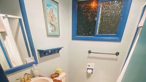 Um banheiro com pia, vaso sanitário e janela com vista para o céu noturno.