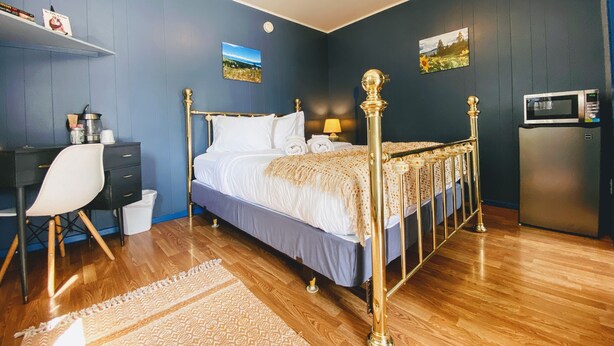 Quarto com cama, escrivaninha, cadeira, micro-ondas e um pequeno frigorífico.