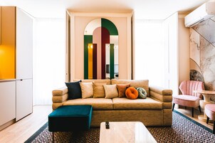 Uma sala de estar moderna com sofá, apoio para os pés e mesa de centro. Há uma TV sobre a mesa de centro.