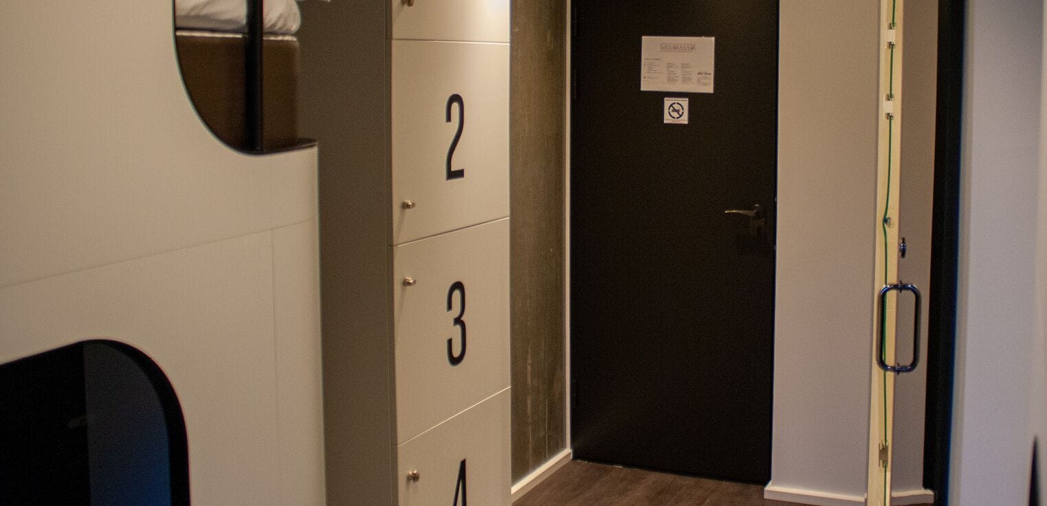 Corredor com armários individuais numerados e uma porta com placa de proibido fumar.