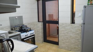 Uma cozinha compacta com fogão, pia e chaleira no balcão.