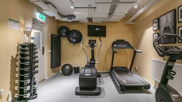 Uma academia com equipamentos de ginástica, incluindo esteira, elíptico e aparelhos de musculação.