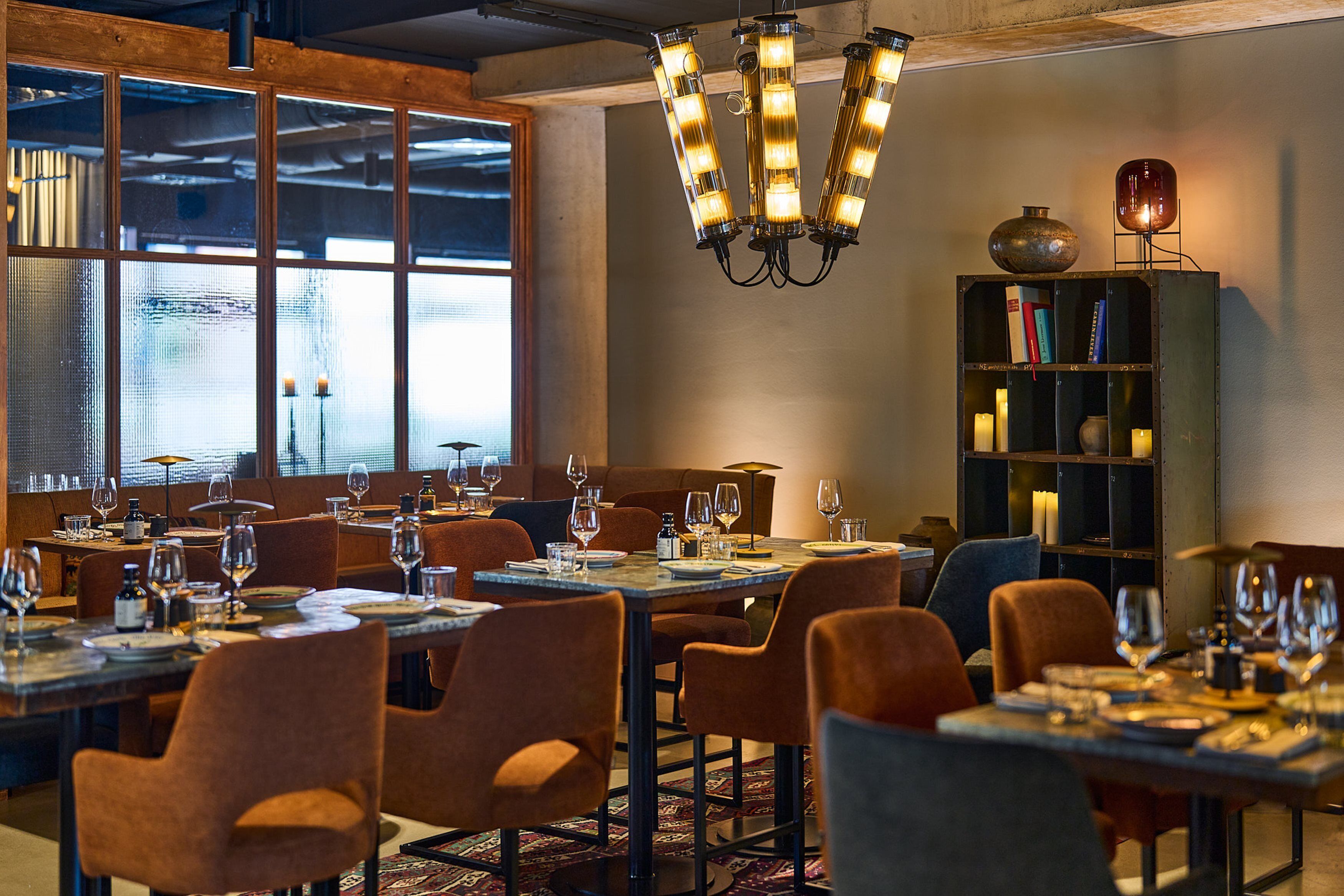 Restaurante com mesas preparadas para refeições, um candelabro e uma estante com velas.