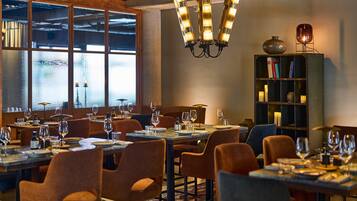 Restaurante com mesas preparadas para refeições, um candelabro e uma estante com velas.
