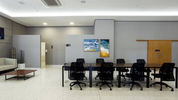 Uma sala de conferências com uma mesa comprida, seis cadeiras, um sofá e obras de arte nas paredes.