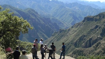 Um grupo de pessoas está em uma rocha, apreciando a vista de uma paisagem montanhosa.