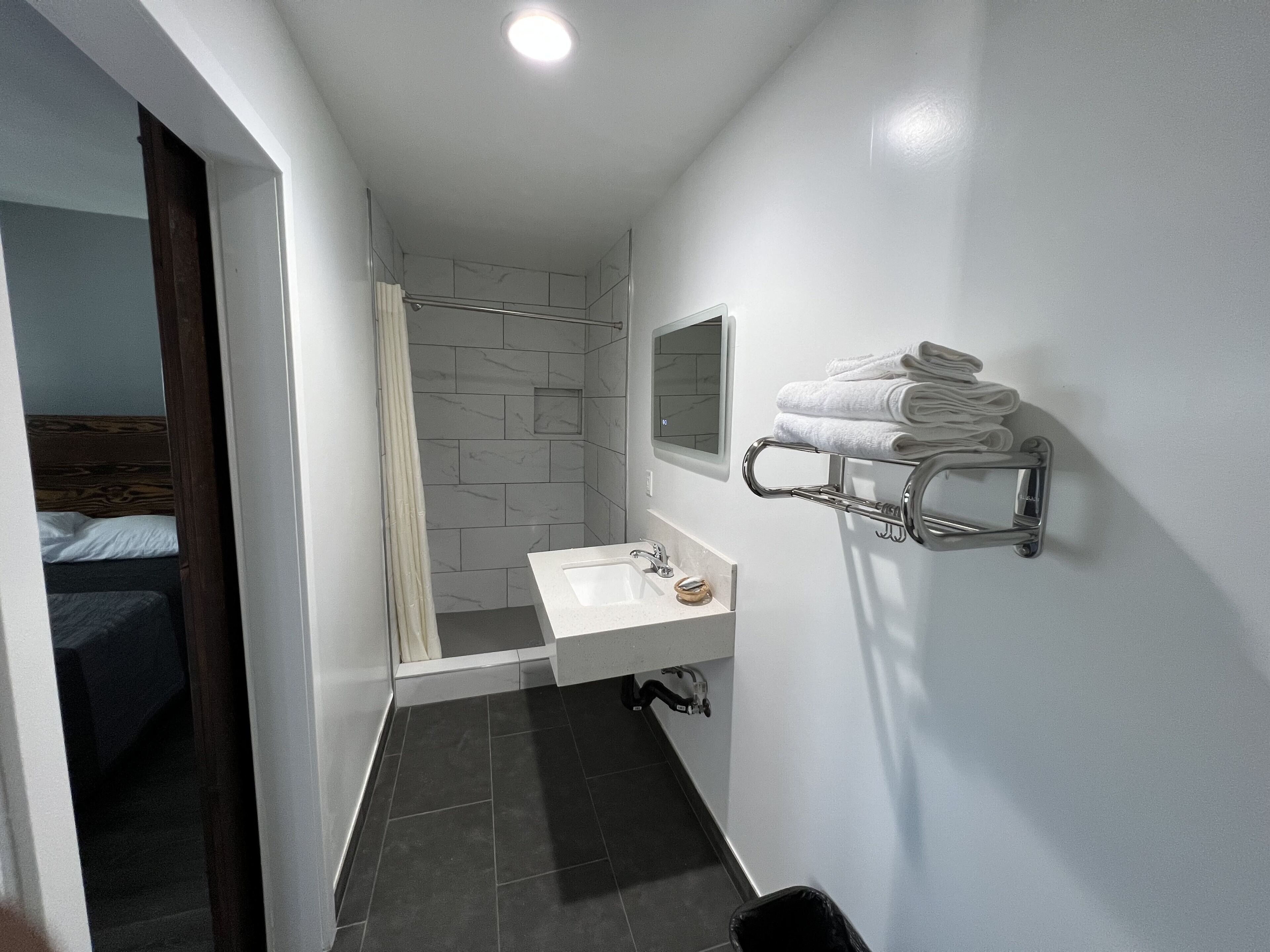 Uma casa de banho moderna com chuveiro, pia e porta-toalhas.