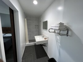 Uma casa de banho moderna com chuveiro, pia e porta-toalhas.