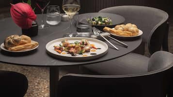 Uma mesa de jantar com pratos de comida, copos de vinho e talheres.