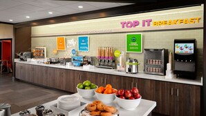 Espaço de buffet de café da manhã com diversos alimentos e uma máquina de café.