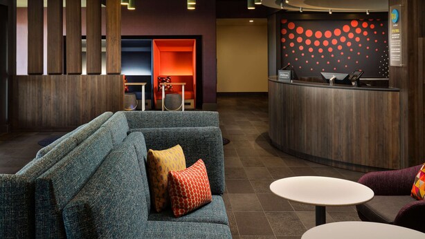 Um lobby moderno de hotel com uma mesa de recepção, área de estar e luminárias de design exclusivo.