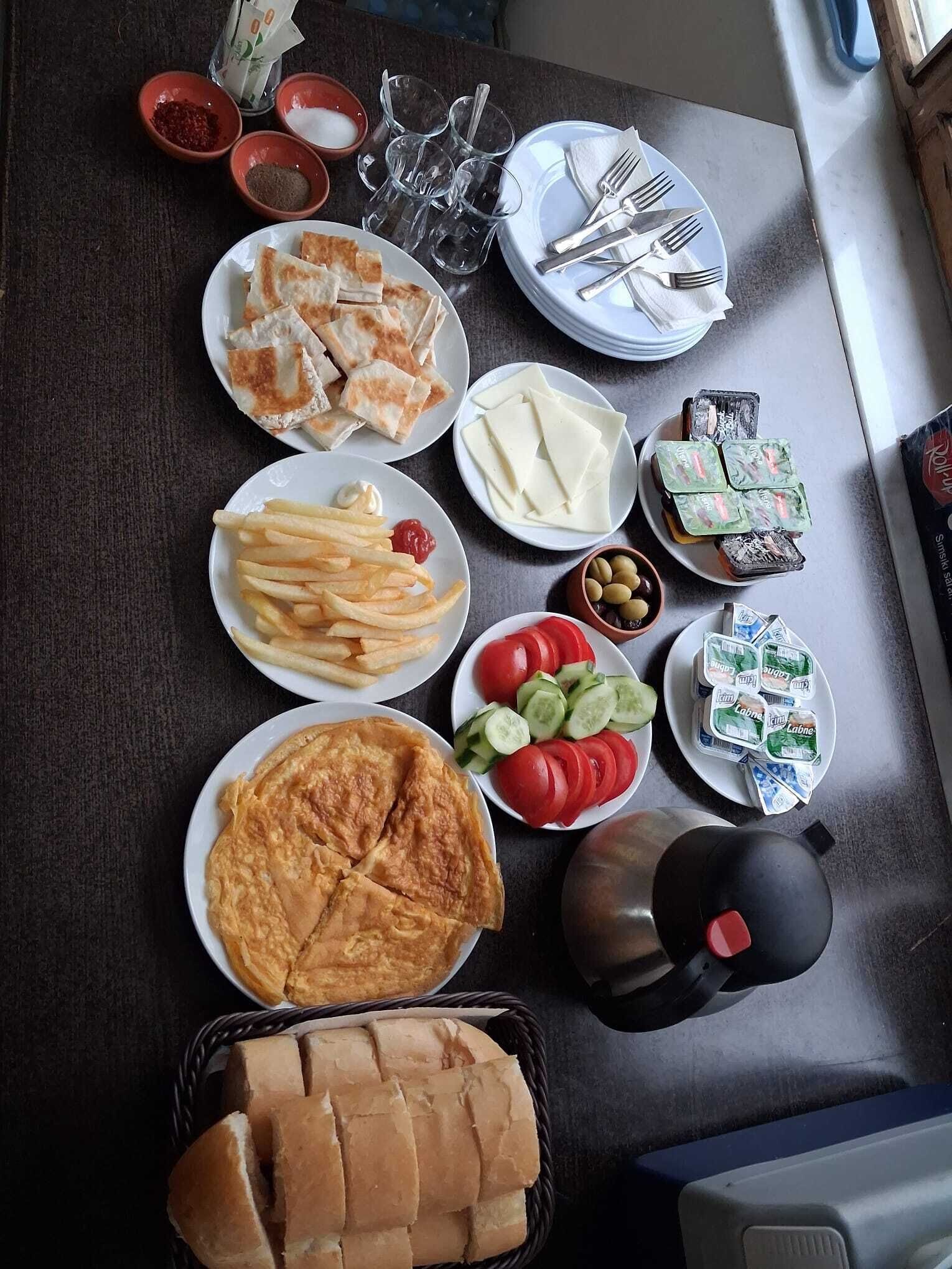Uma mesa com diversos alimentos e acompanhamentos, incluindo pão, queijo e uma cesta de pães.