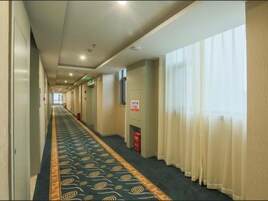 Corredor de hotel com carpete estampado, um extintor de incêndio e uma placa na parede.