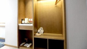Um closet espaçoso com cabideiro, prateleira para produtos de higiene pessoal e sapateira.