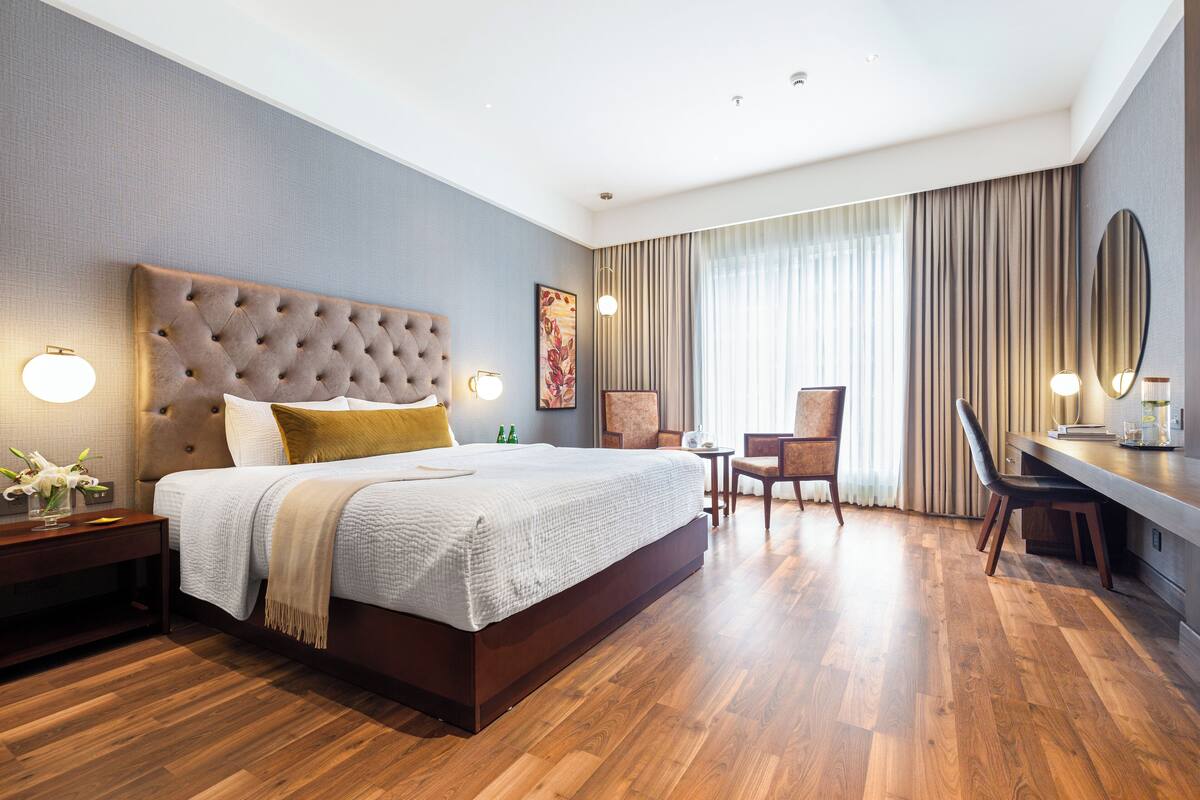 Quarto de hotel moderno com uma cama grande, uma escrivaninha e uma cadeira.