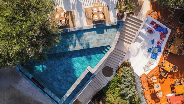 Vista aérea de um resort com piscina central, várias áreas de estar e vegetação exuberante.