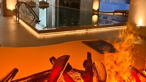 Uma área de spa moderna com lareira, parede de vidro com vista e espaço para relaxar.