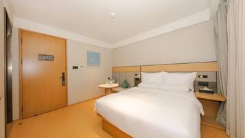 Quarto de hotel com uma cama, mesa de cabeceira e uma porta.
