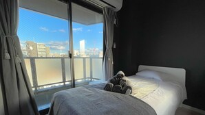Quarto de hotel com cama, janela com vista para edifícios e varanda.