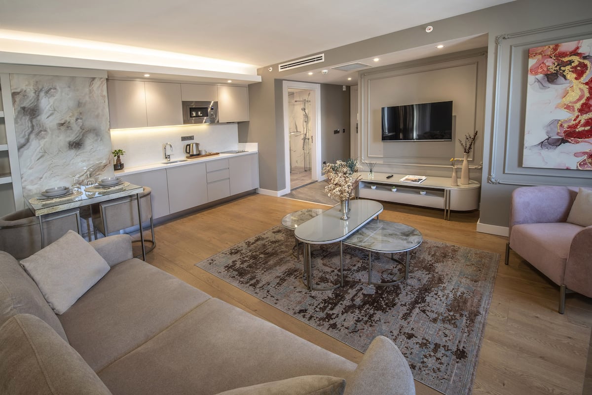 Uma sala de estar moderna com sofá, mesa de centro e área de jantar com mesa posta para dois.