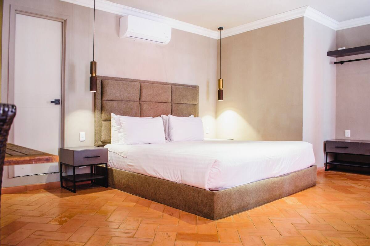 Quarto com uma cama grande, mesa de cabeceira, uma cadeira e um guarda-roupa.
